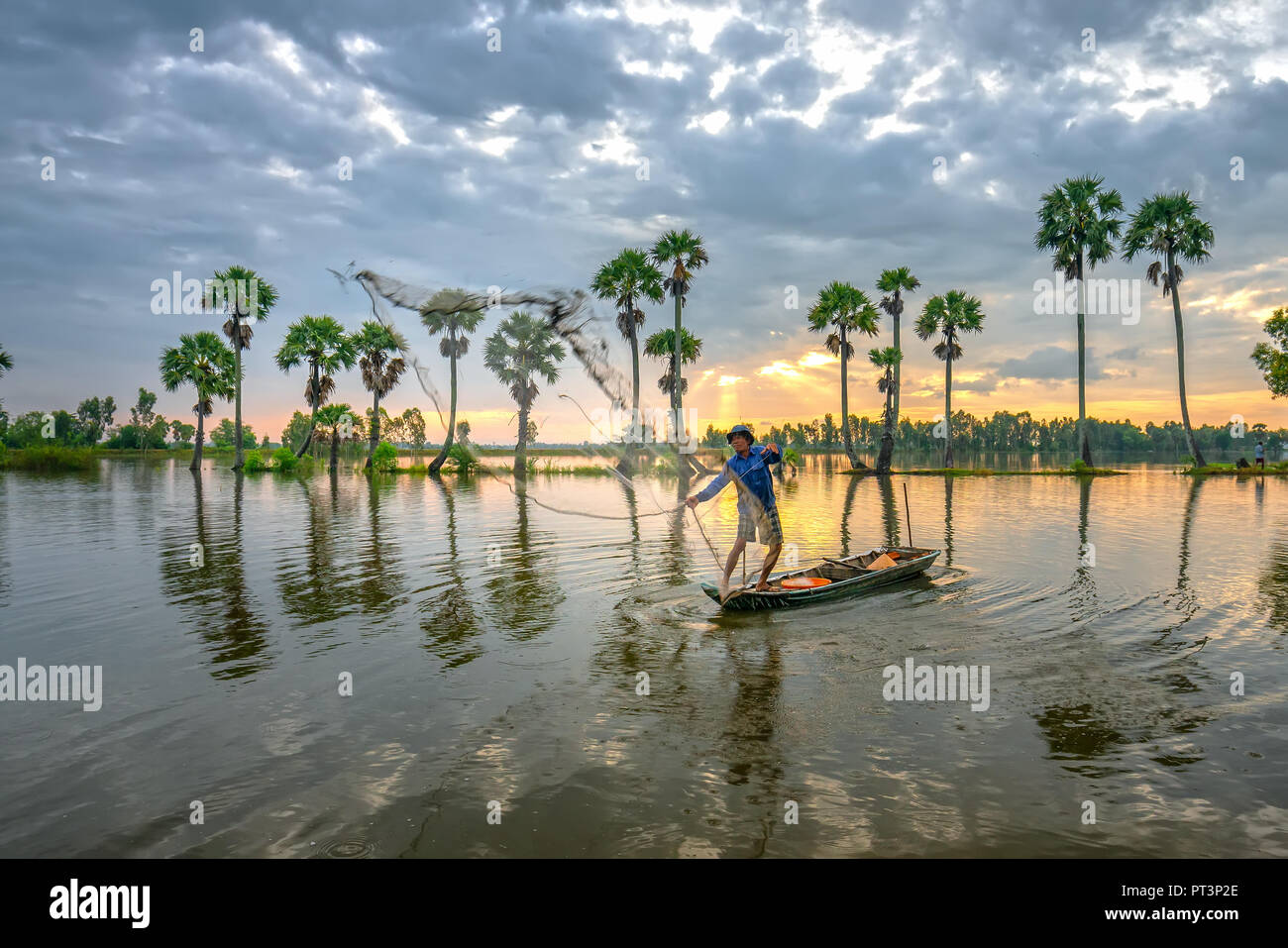 Unidentified fishers throw fish net to catch fish a lake in the morning ...
