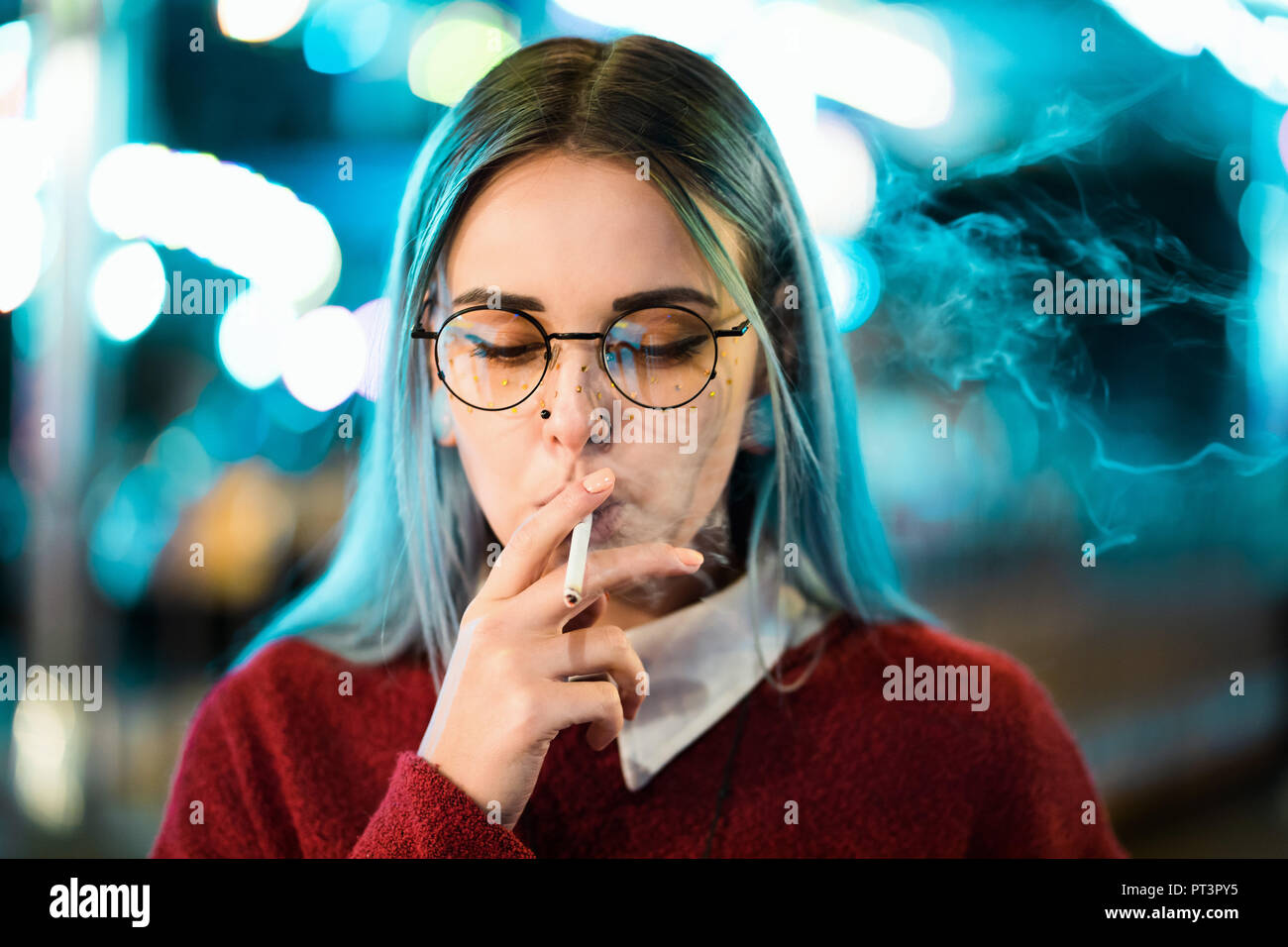 Millennial pretty girl with unusual dyed hairstyle smoking cigarette in ...