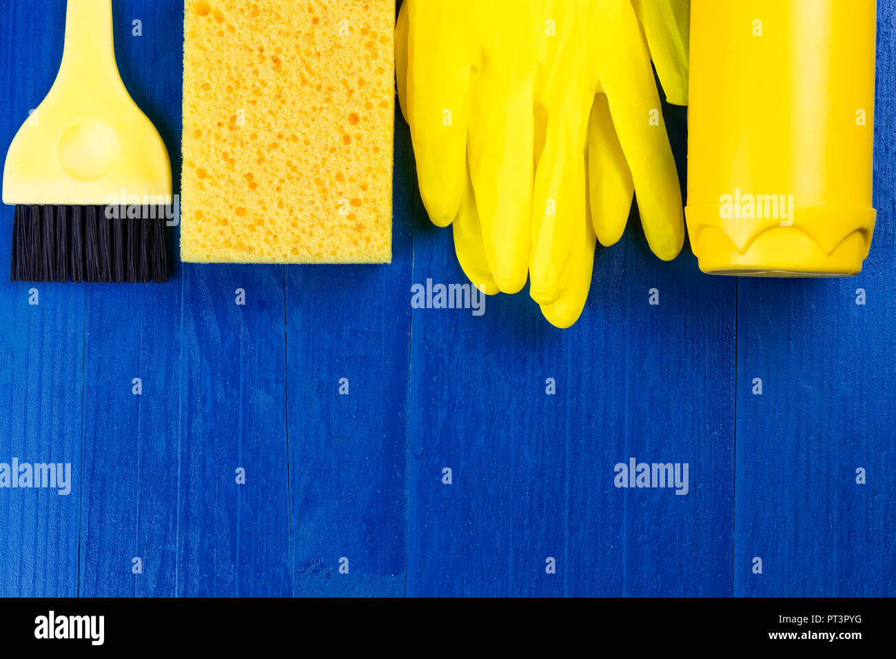 Yellow cleaning supplies on a blue background. Copy space at the bottom ...
