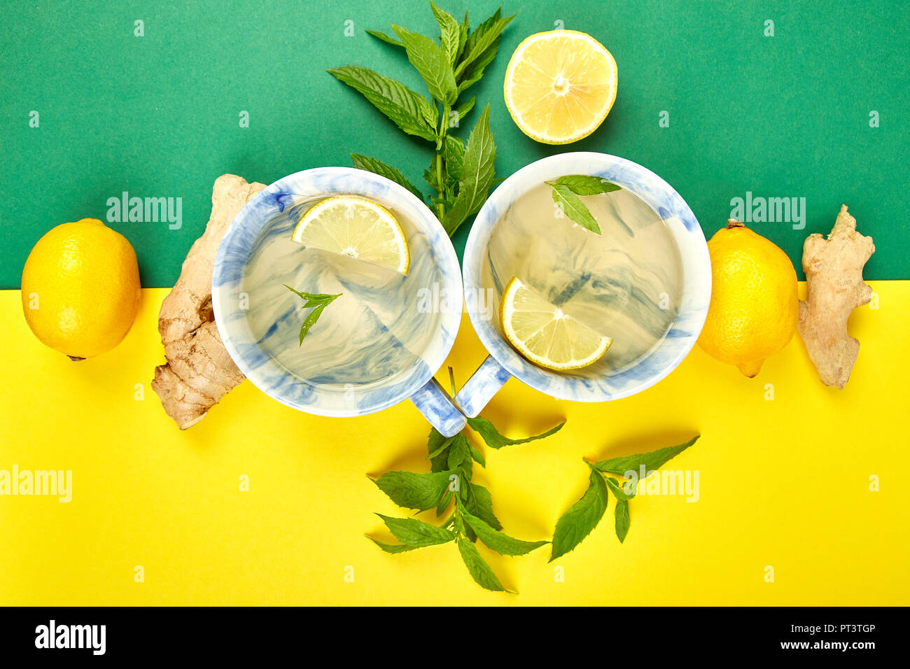 Healthy tea two cups with lemon, ginger, mint on a color background ...