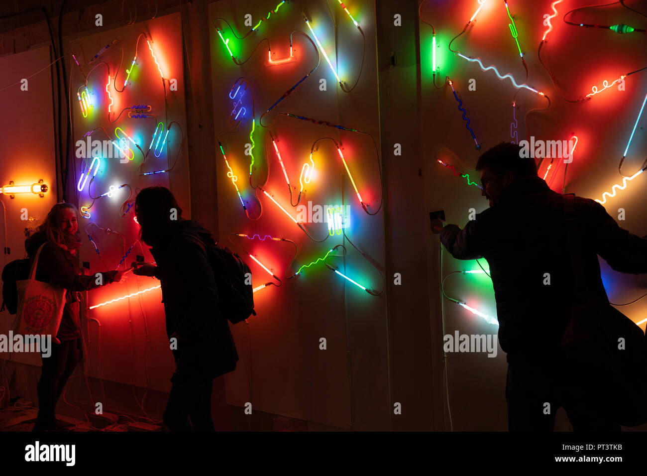 Three people enjoying neon light display at Leeds Light Night West ...