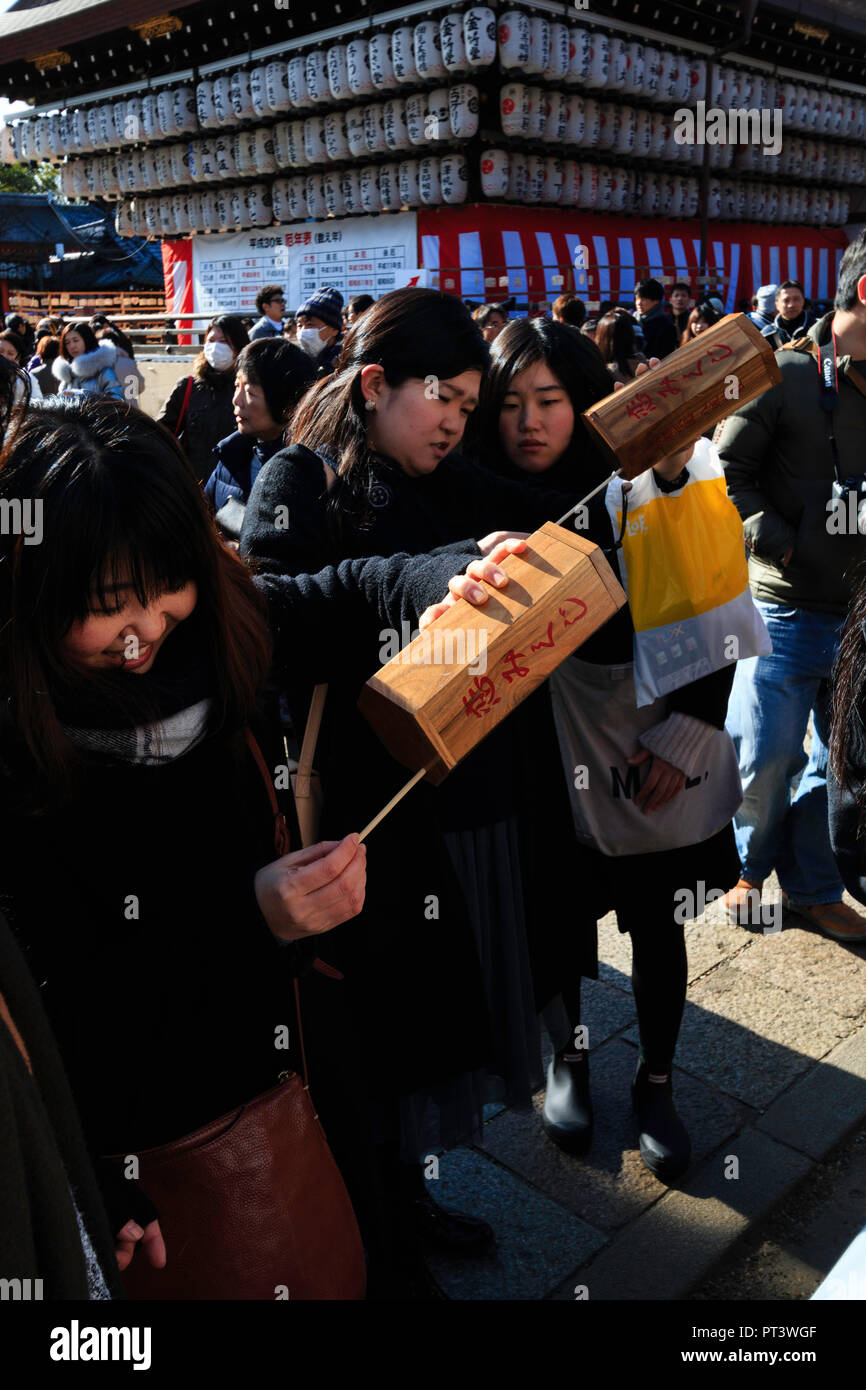 Women shaking omikuji boxes before taking out the paper fortune slip at ...