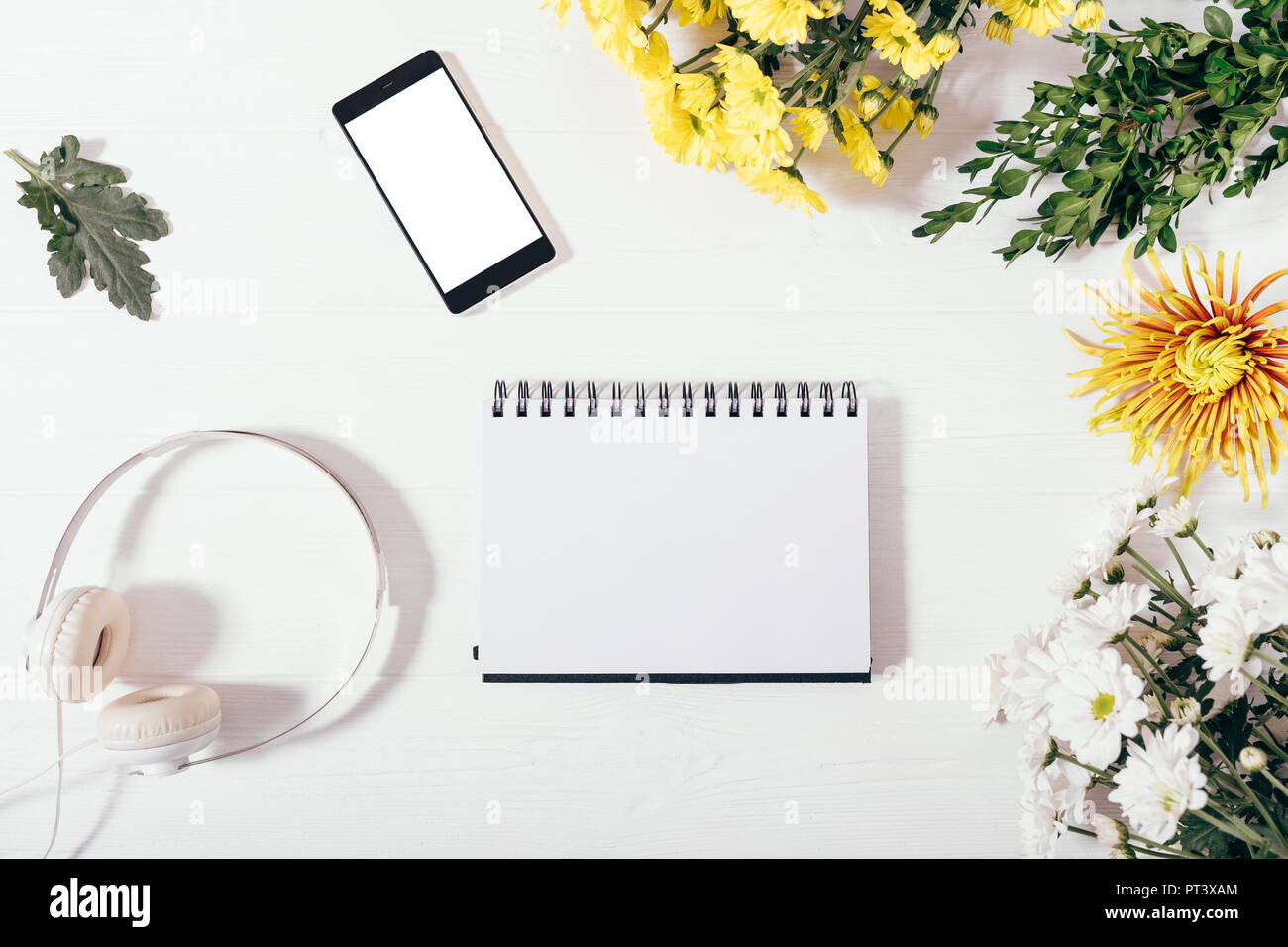 Floral flat lay composition with smart device, earphones and empty ...