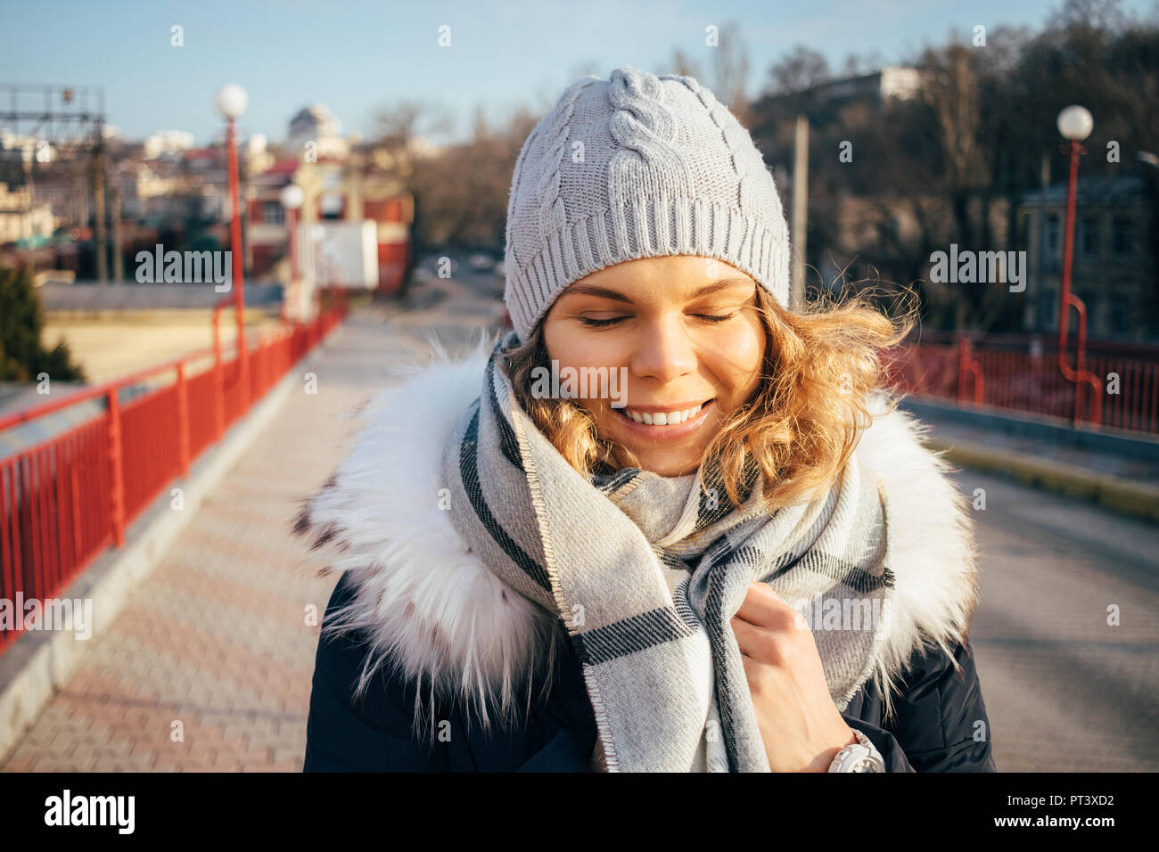 Portrait of young woman wearing down jacket and hat standing outdoors ...