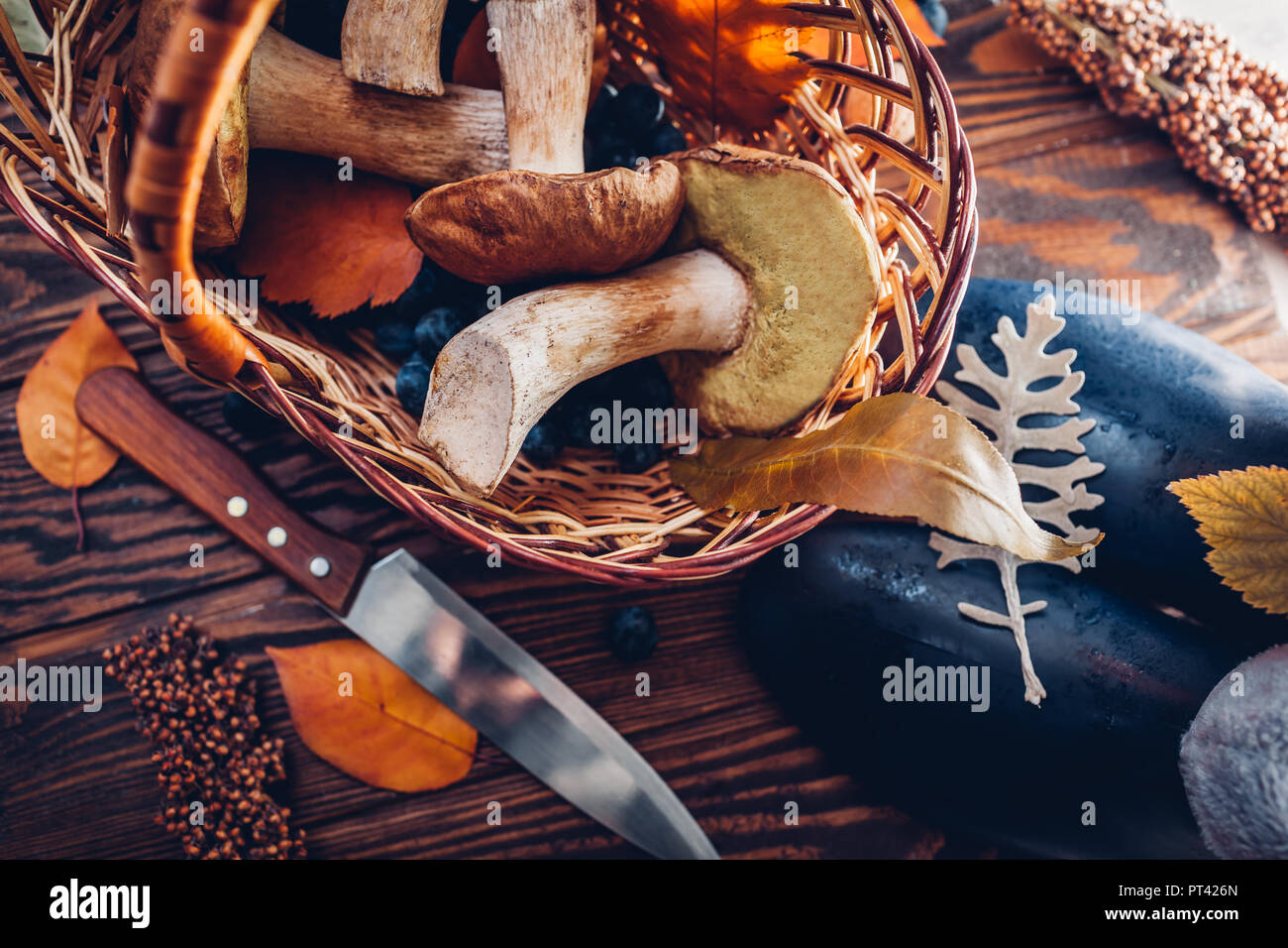 Porcini mushrooms in basket with berries and nuts on wooden table ...