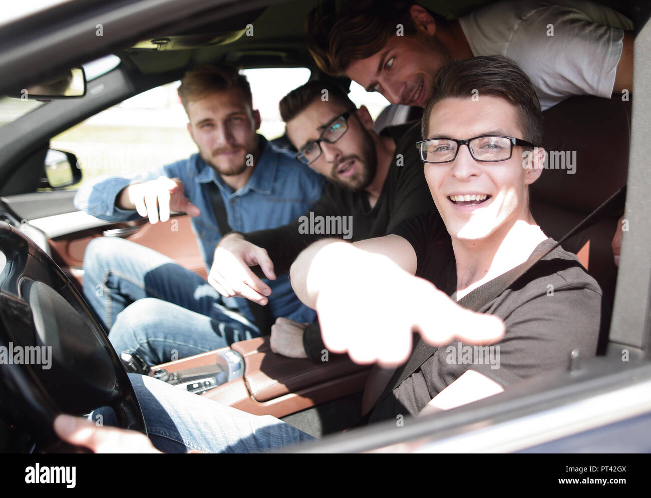 young guys sitting in the car greeting friends waving from the window ...