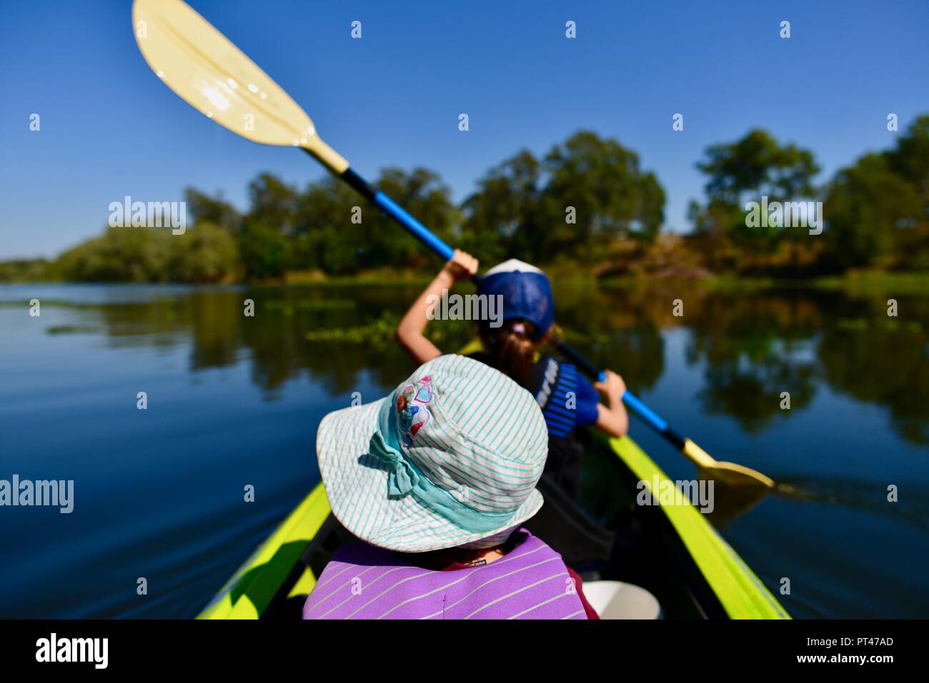 Children paddling in a canoe in beautiful weather, Ross River QLD ...