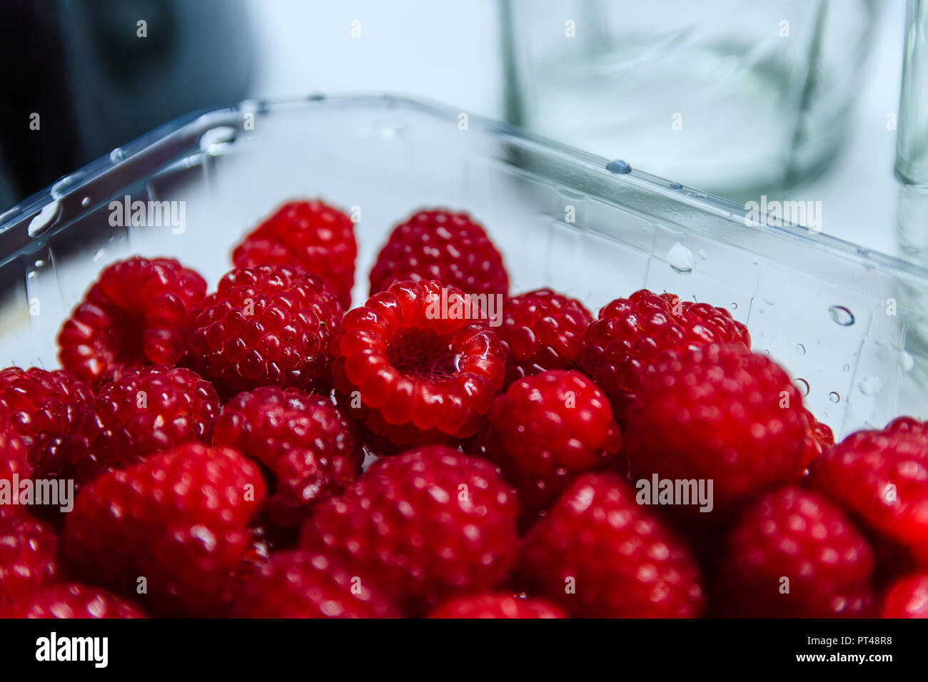 Red bright raspberry in plastic box with waterdrops Stock Photo - Alamy