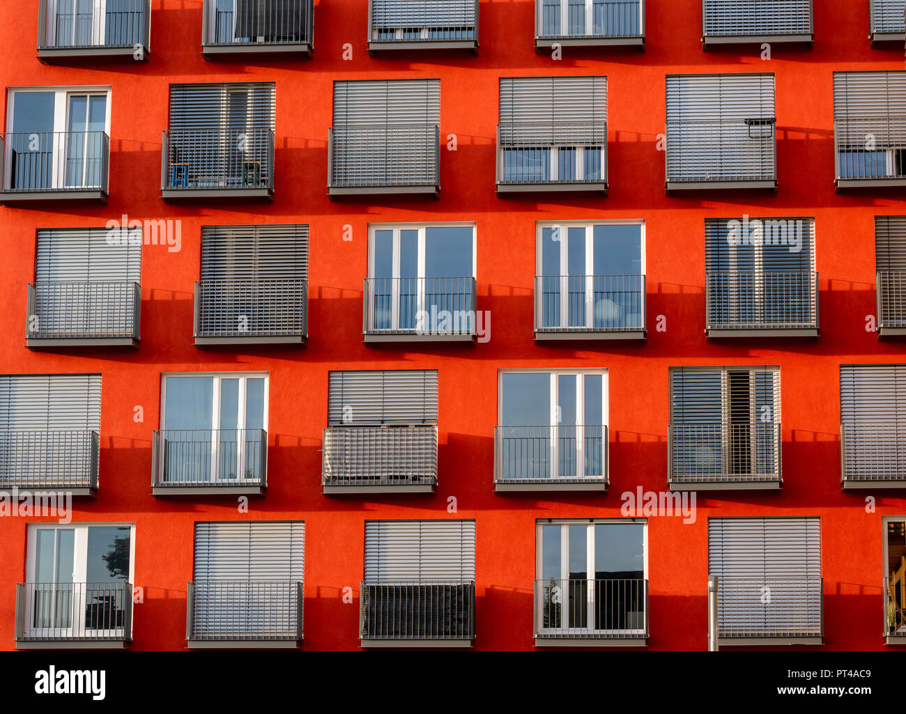 Close up image of red high rise building with windows and balconies and ...