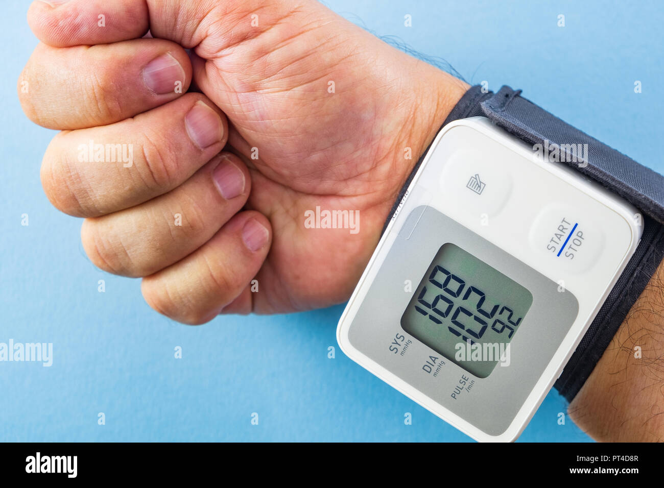 Male hand wearing white and grey electronic wrist blood pressure ...