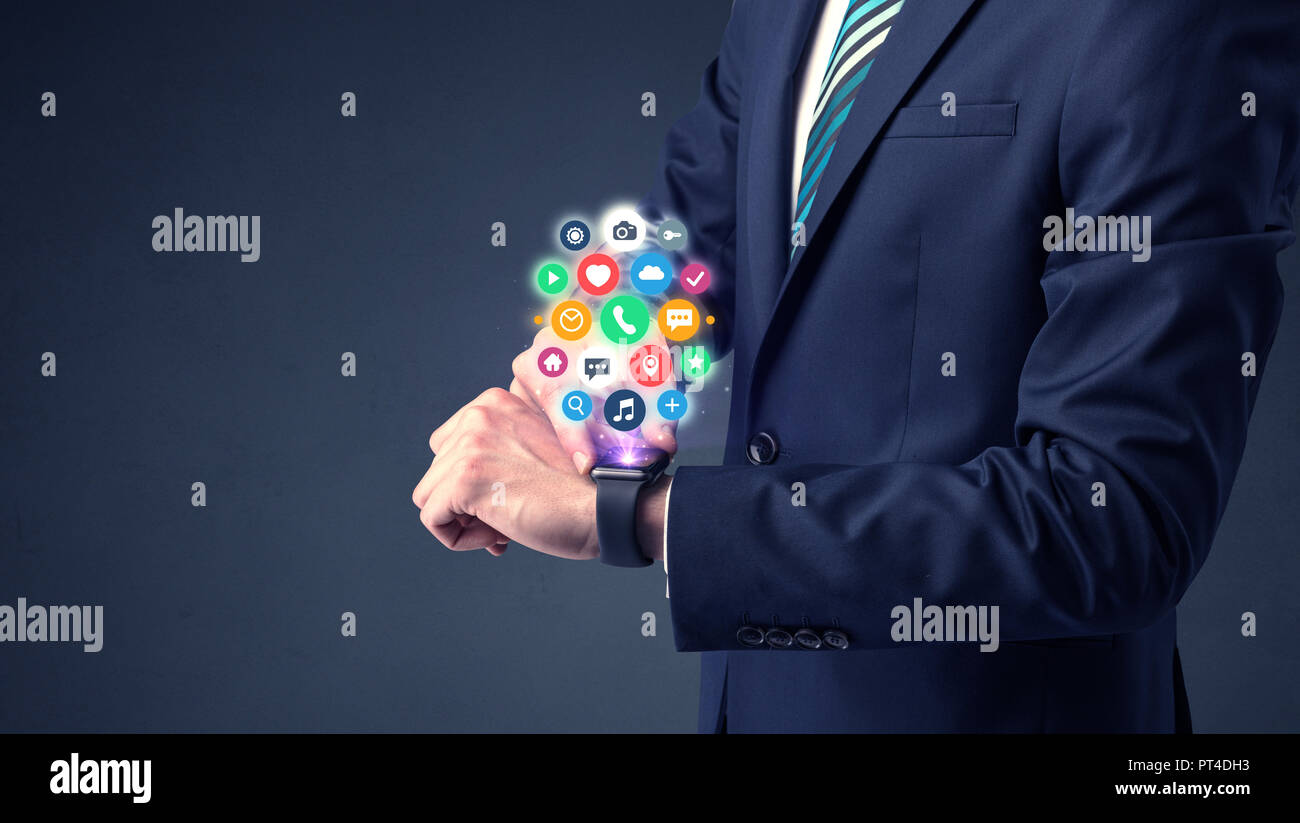 Businessman wearing smartwatch with colored application symbols on it ...