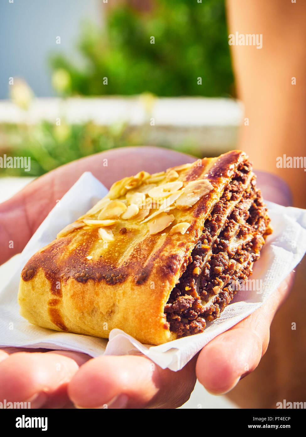 A female hand holding a portion of Kokosh, chocolate roll pastry, from ...