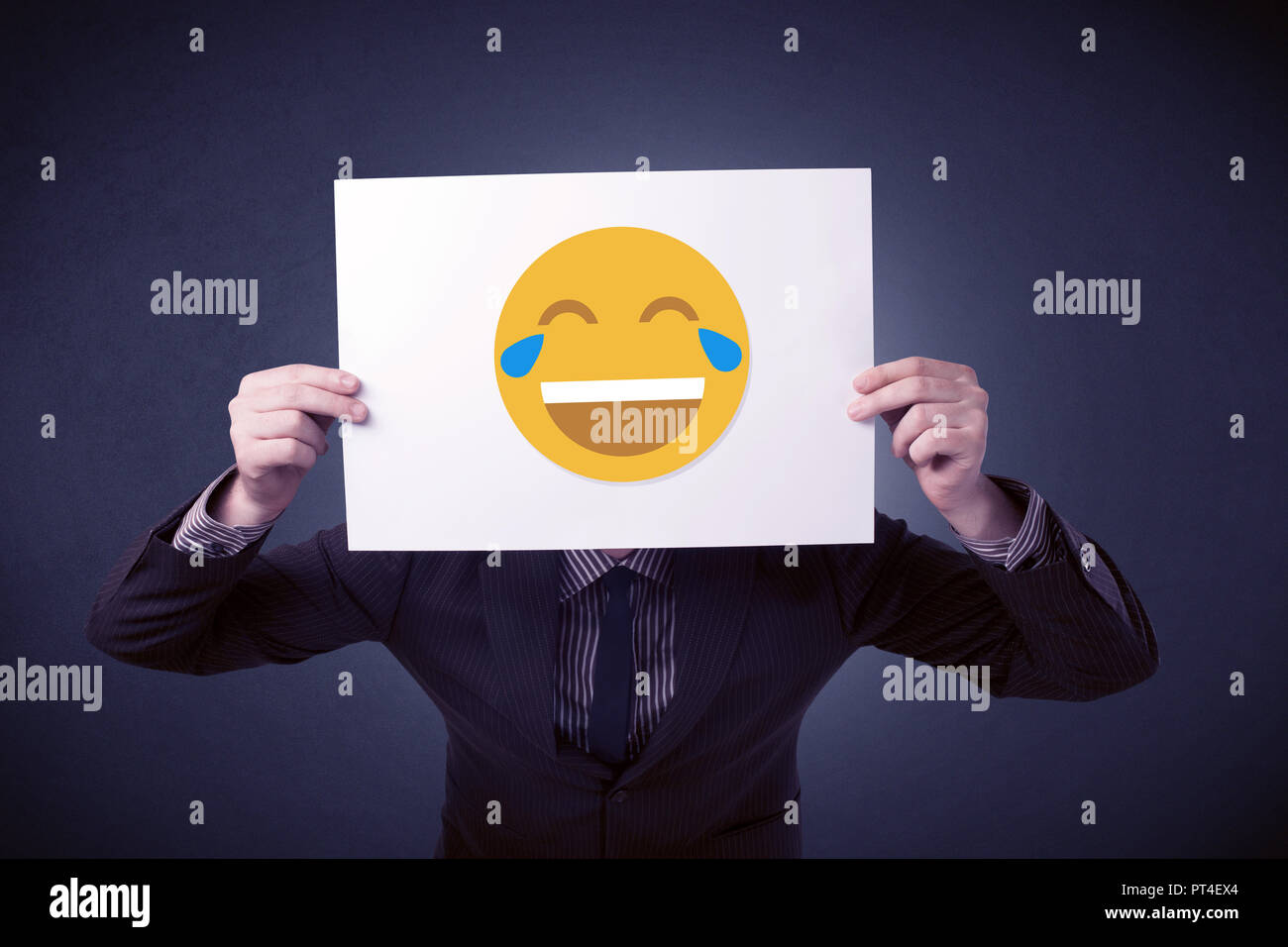 Young businessman hiding behind a laughing emoticon on cardboard Stock ...