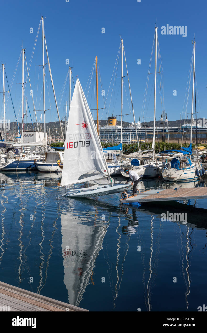 Man putting sailing dinghy into water Stock Photo - Alamy