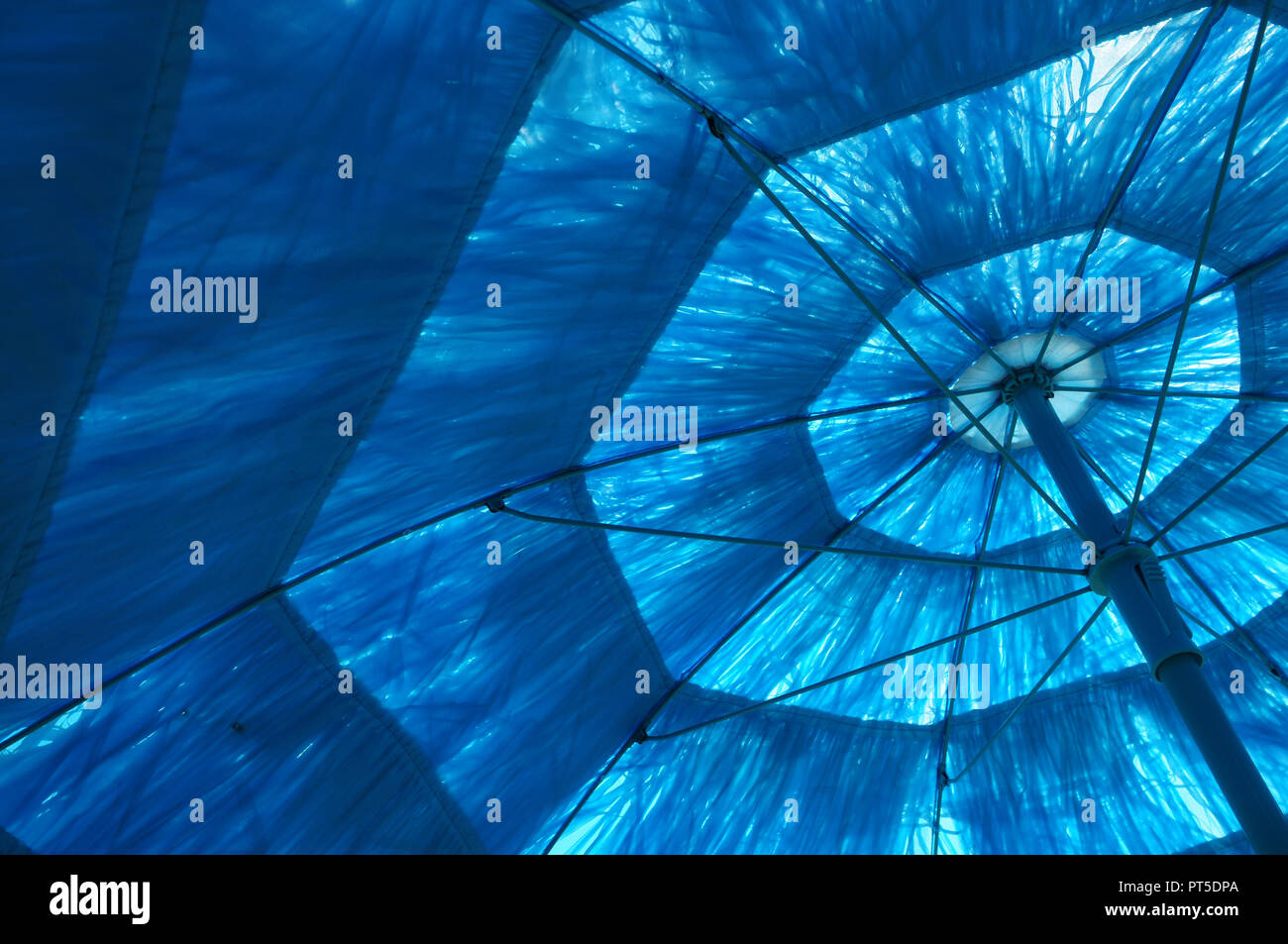 Light shining through feathered sun umbrella creating geometric ...