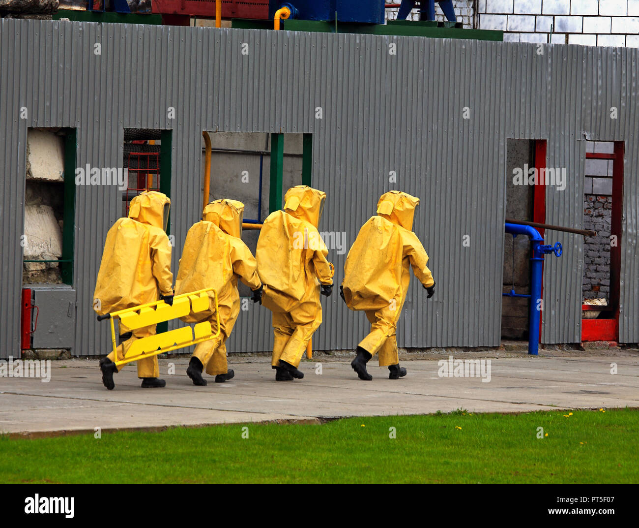 A group of four rescuers in the protective clothing in the industrial ...