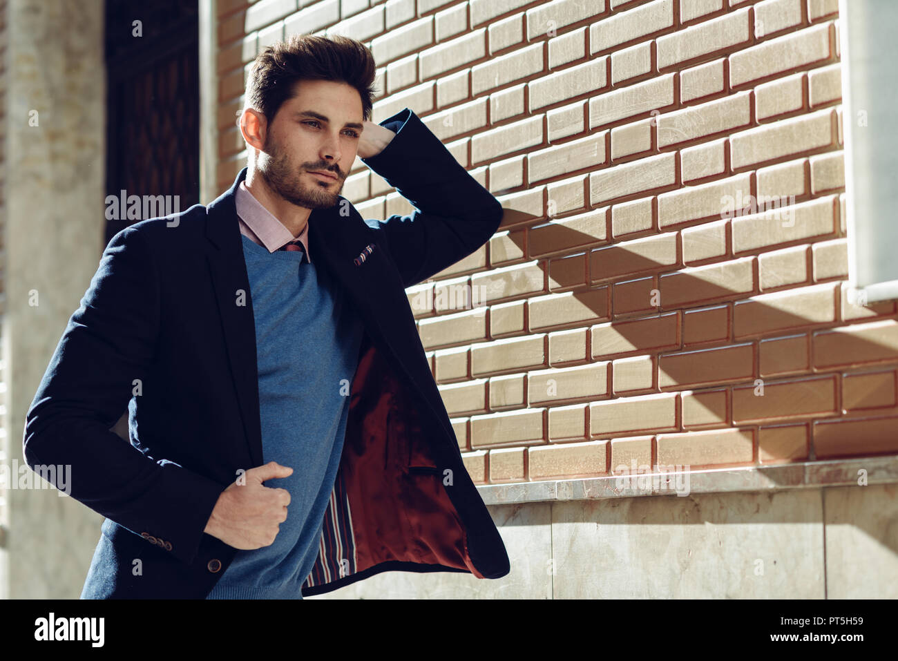 Attractive man in the street wearing british elegant suit. Young bearded businessman with modern ...