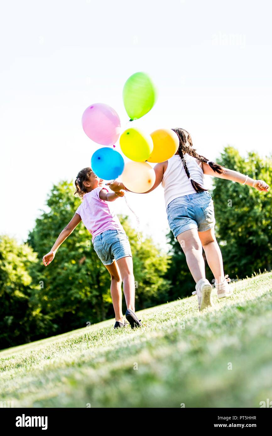 Girls running with balloons in park, smiling Stock Photo - Alamy