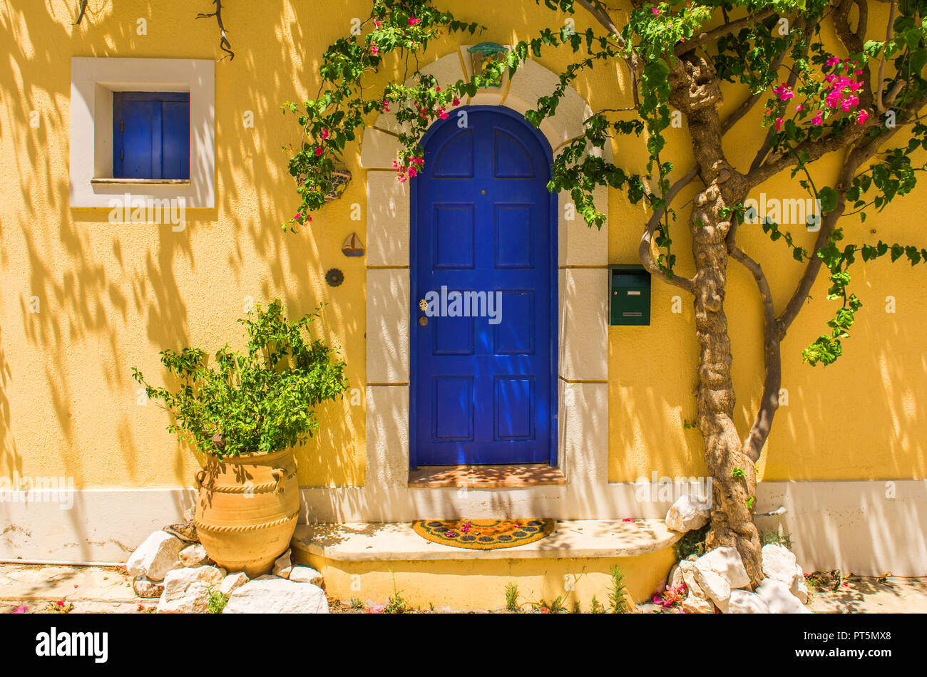Traditional greek house with blue doors and yellow wall Stock Photo - Alamy