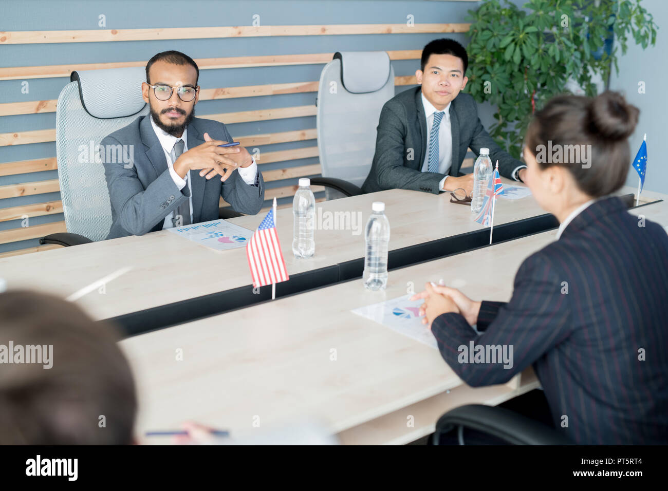 Serious pensive multi-ethnic diplomats in formal suits sitting at ...