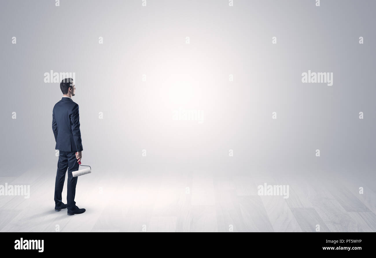 Man standing with his back in an empty room with object in his hand ...