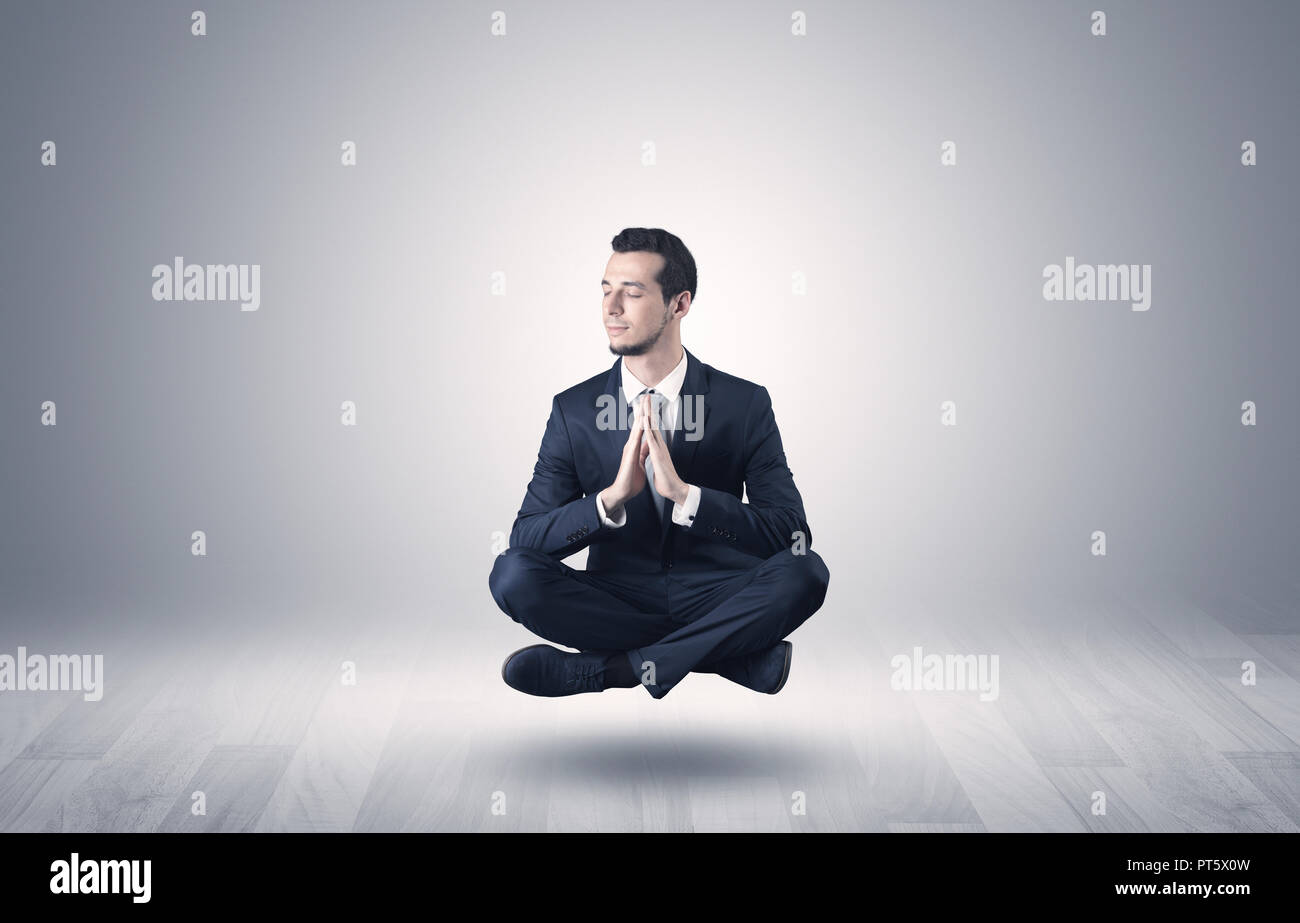 Businessman levitates and sitting in yoga position in an empty infinity ...