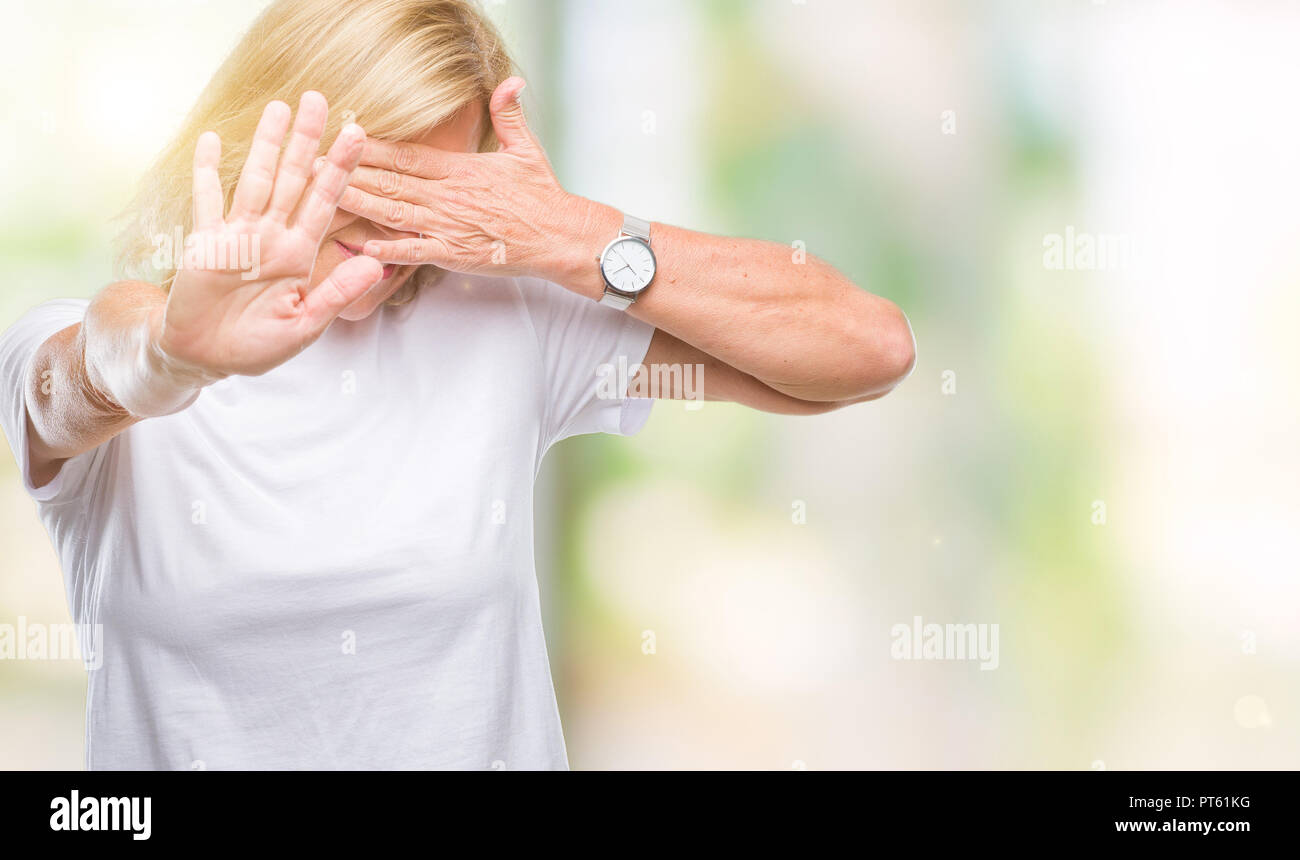 Middle age blonde woman over isolated background covering eyes with ...