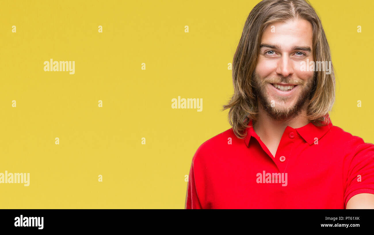 Young handsome man with long hair over isolated background smiling ...