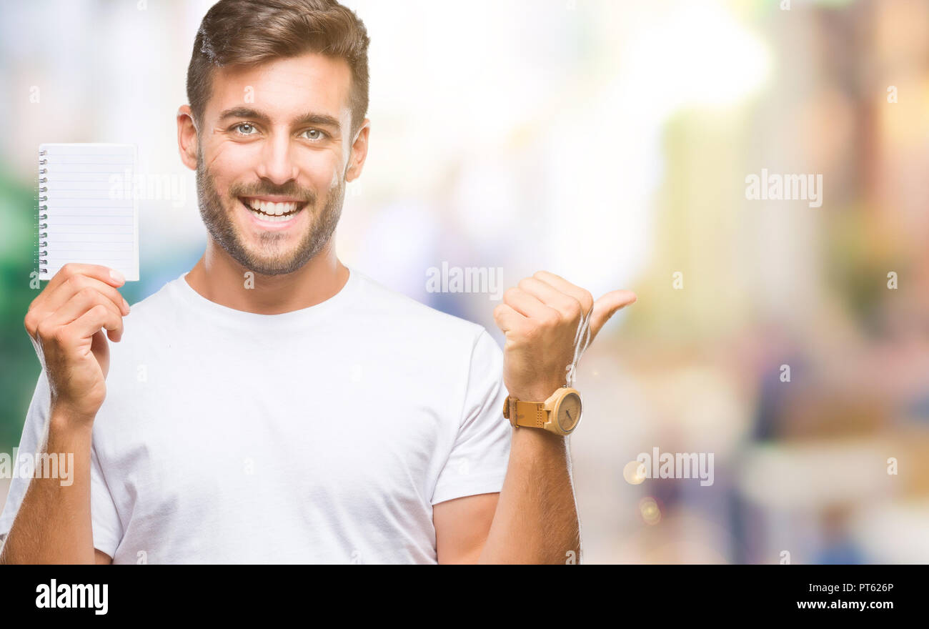 Young handsome man holding notebook over isolated background pointing ...