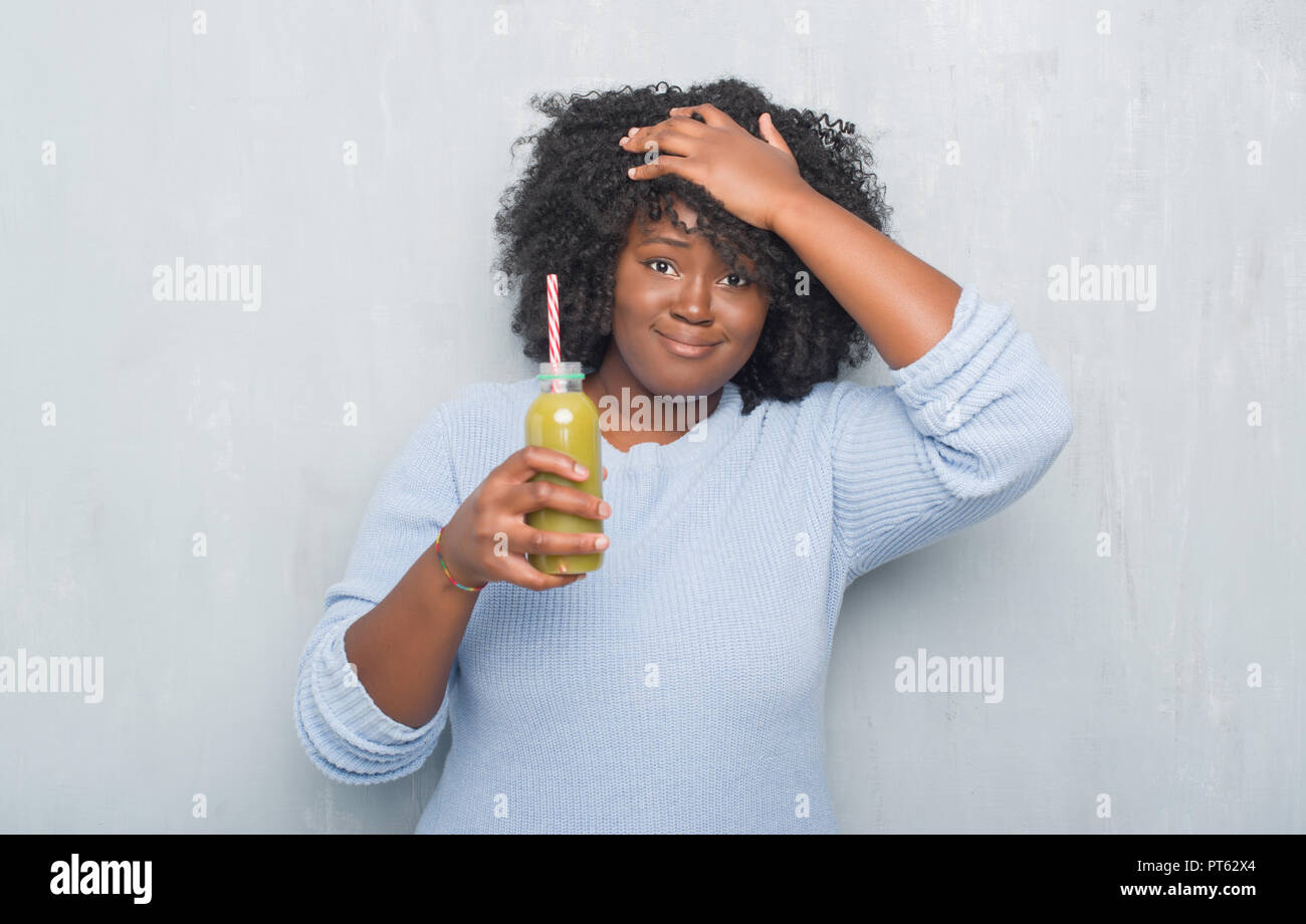 Young african american woman over grey grunge wall drinking detox green ...