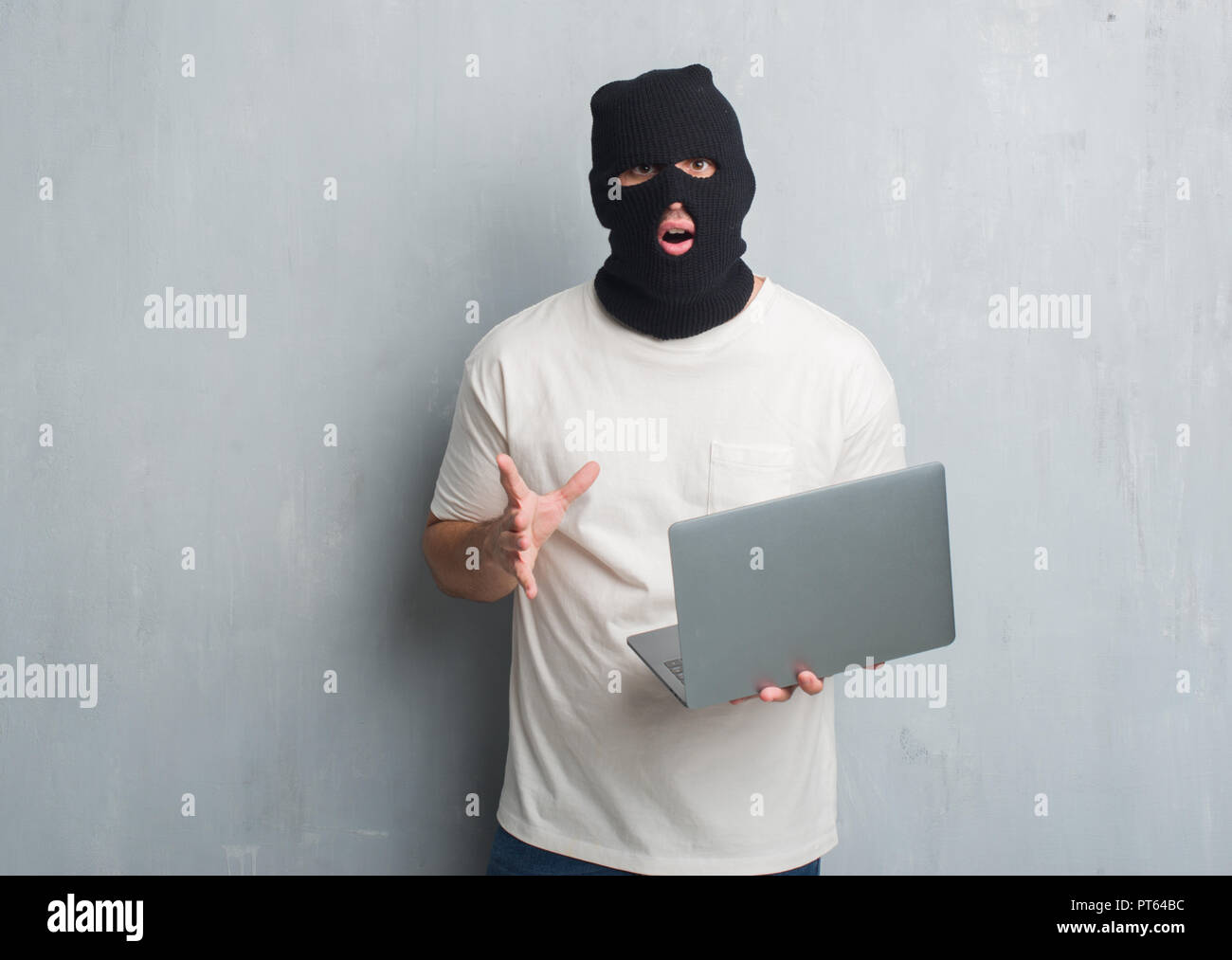 Young caucasian hacker man over grey grunge wall doing cyber attack ...