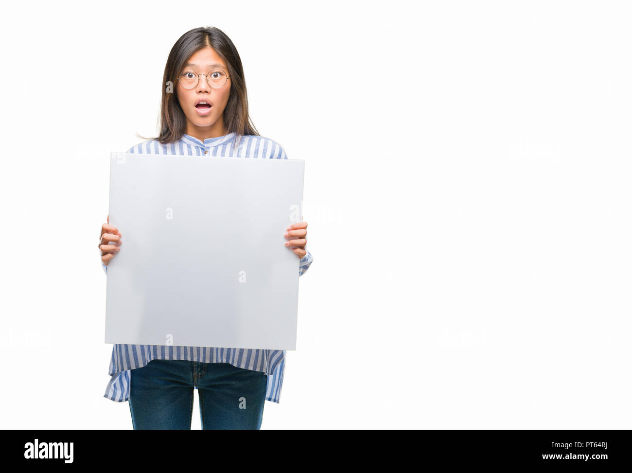 Young asian woman over isolated background holding blank banner scared ...