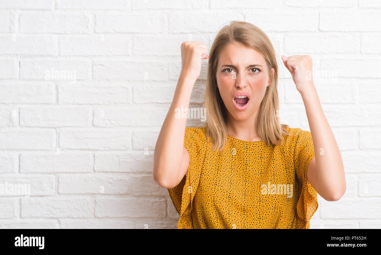 Beautiful young woman over white brick wall annoyed and frustrated ...