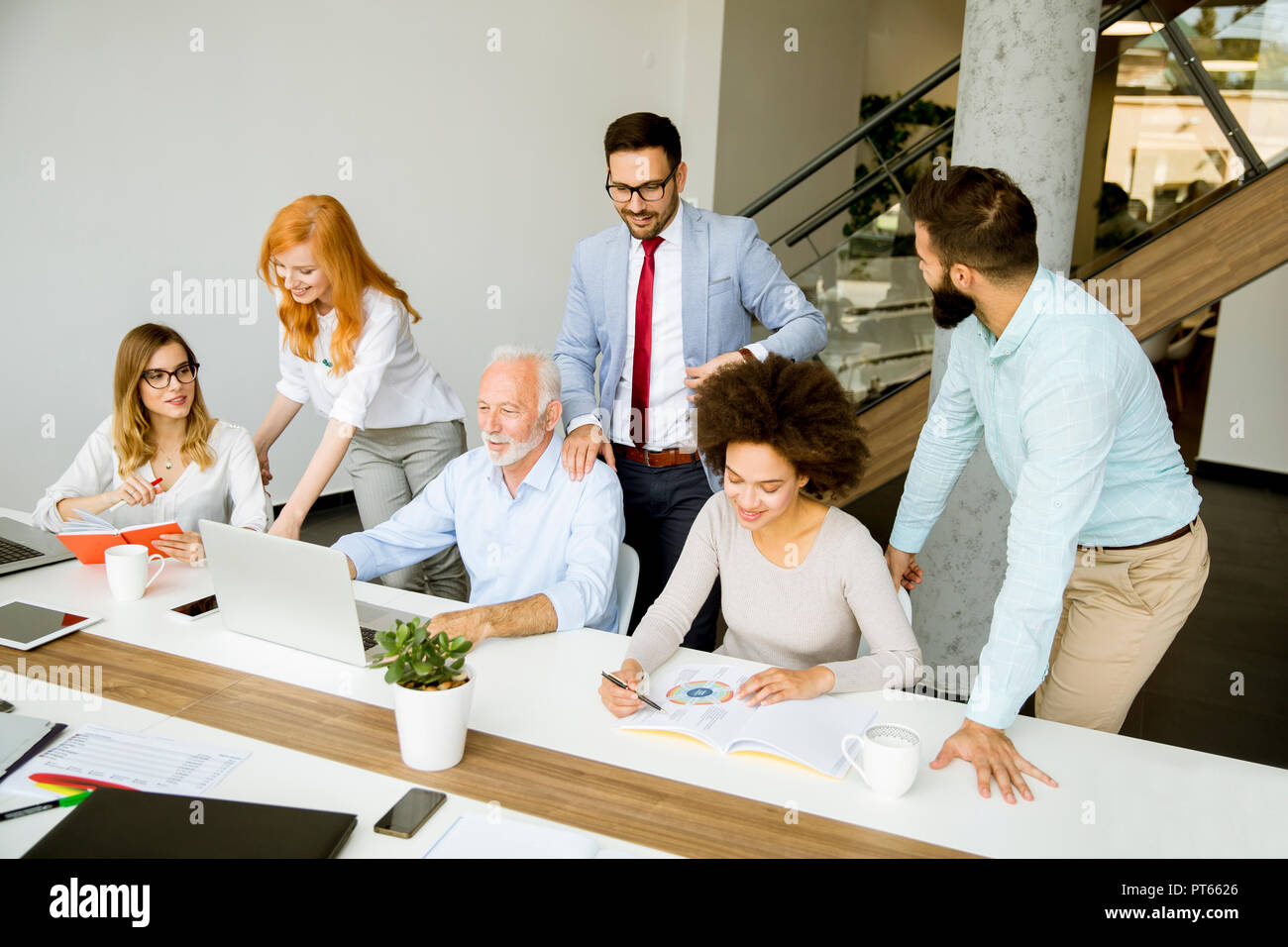 View at group of young multiracial business people around table during ...