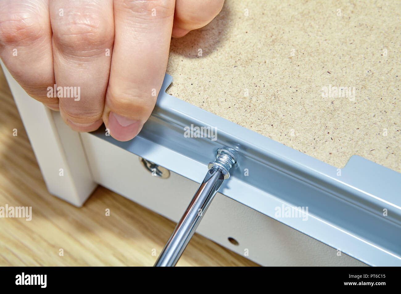 Using furniture fasteners and screwdriver when mounting a drawer, close ...