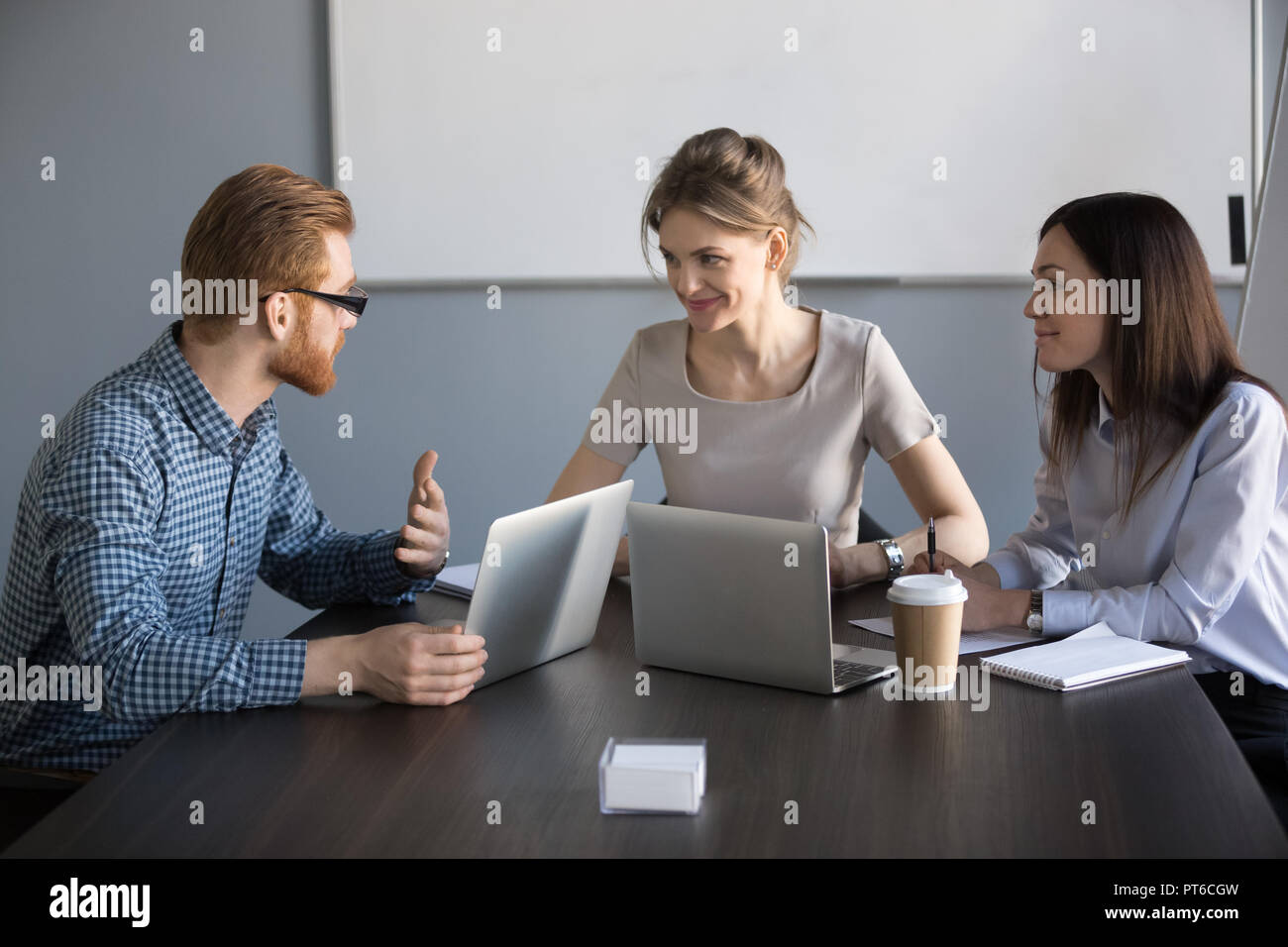 Male colleague explaining smiling female coworkers project plan Stock ...