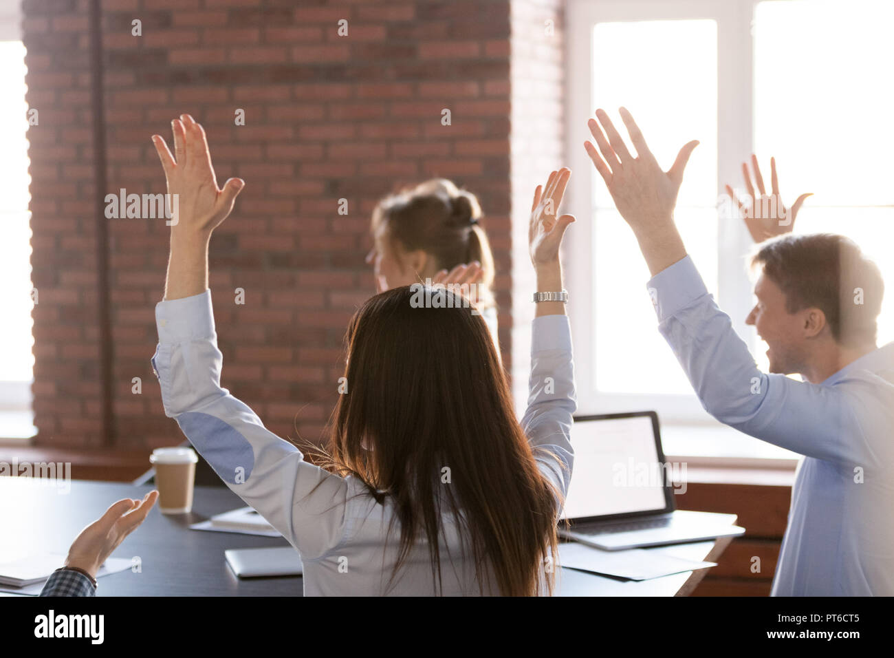 Rear view at happy employees raising hands excited by success Stock ...