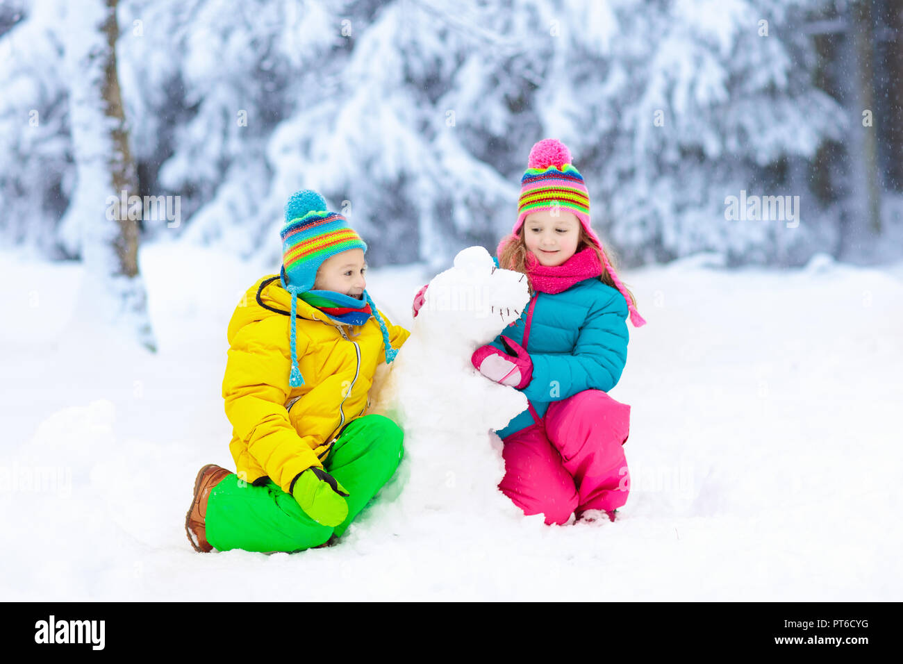 Kids making snowman in snowy winter park. Children play in snow. Boy ...