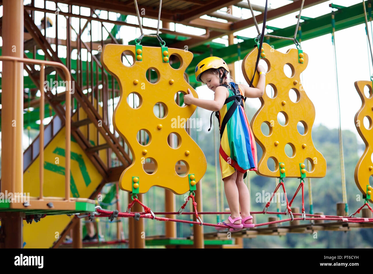 Child in forest adventure park. Kids climb on high rope trail. Agility ...