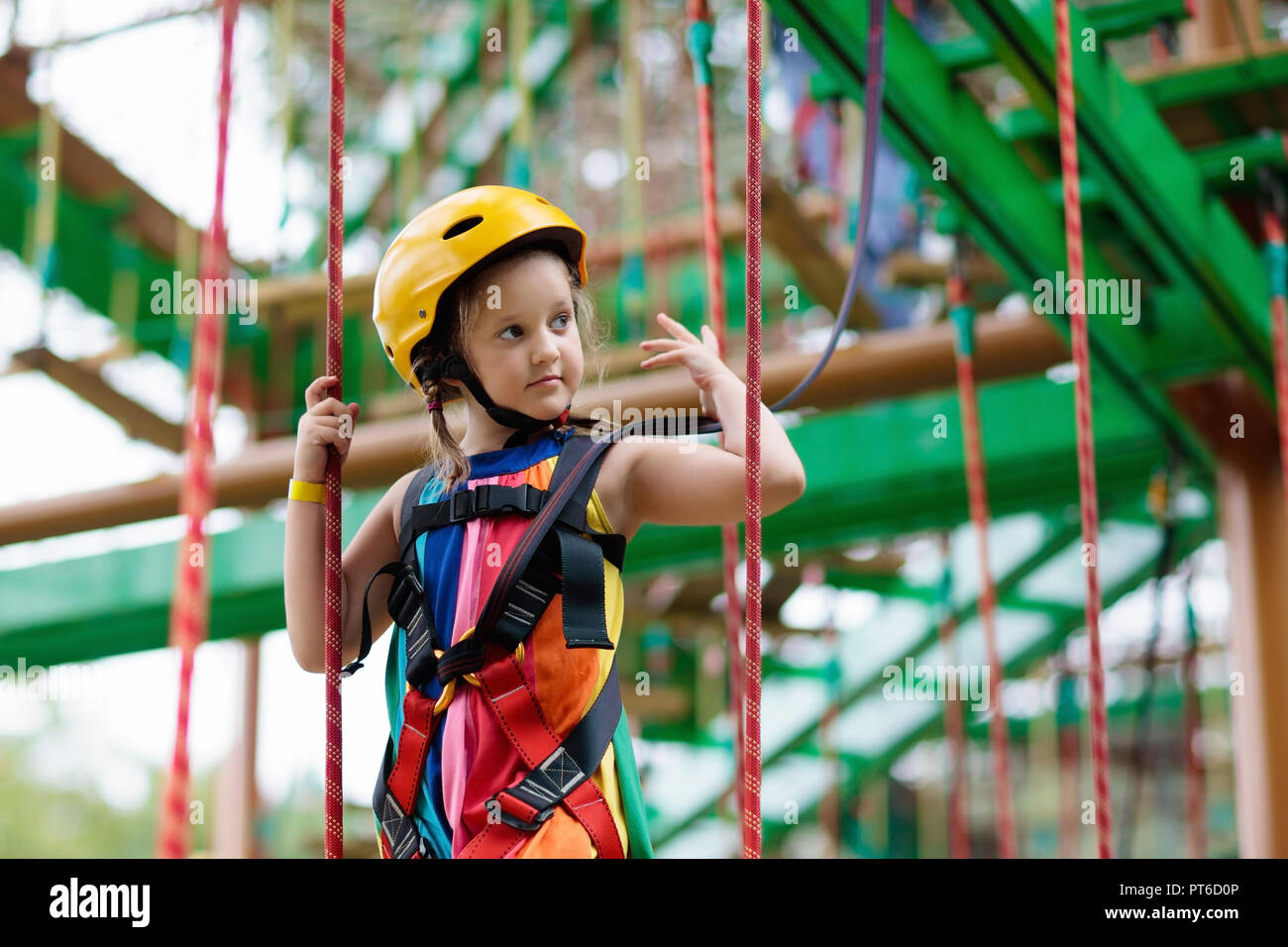 Child in forest adventure park. Kids climb on high rope trail. Agility ...