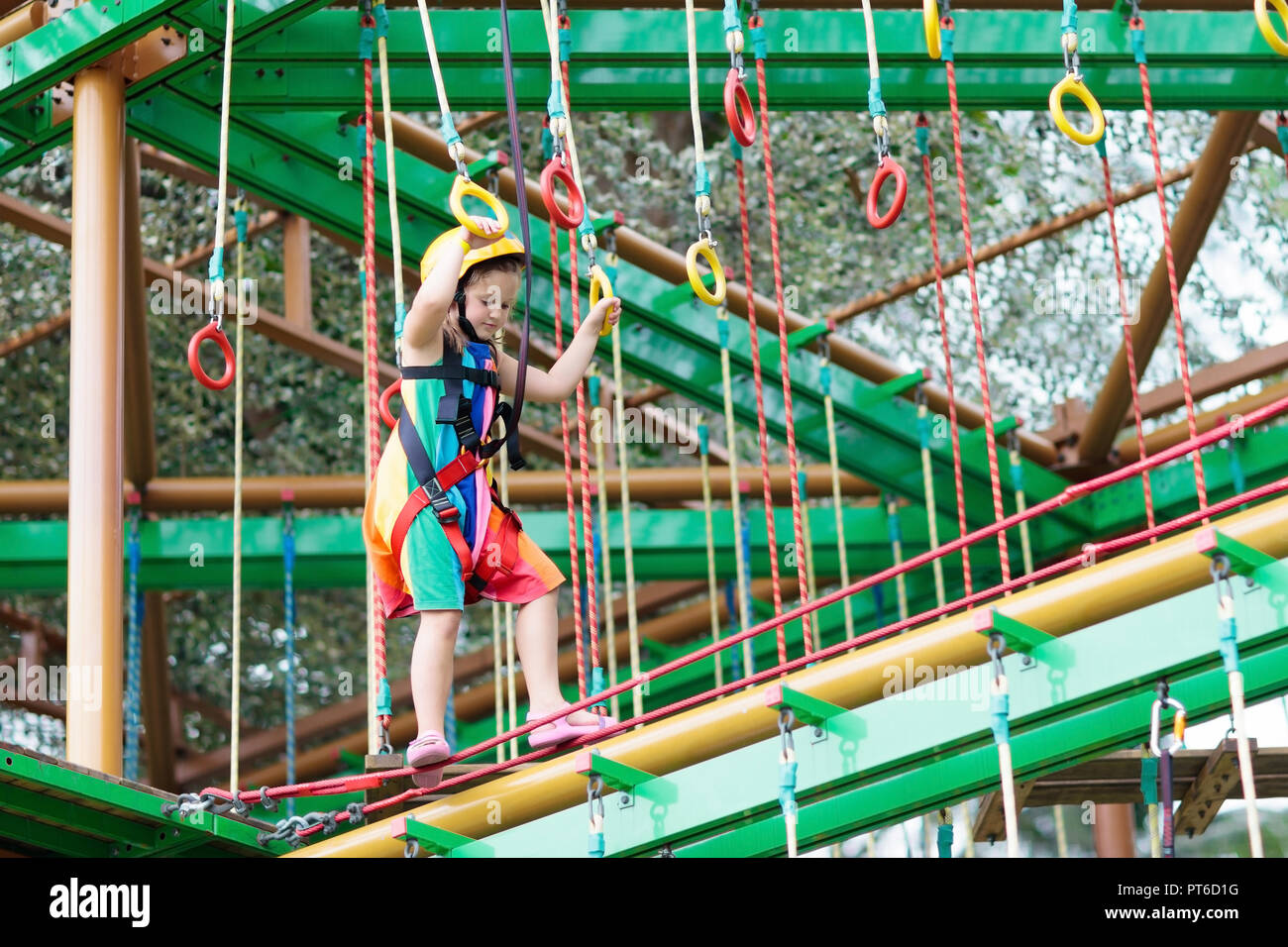 Child in forest adventure park. Kids climb on high rope trail. Agility ...