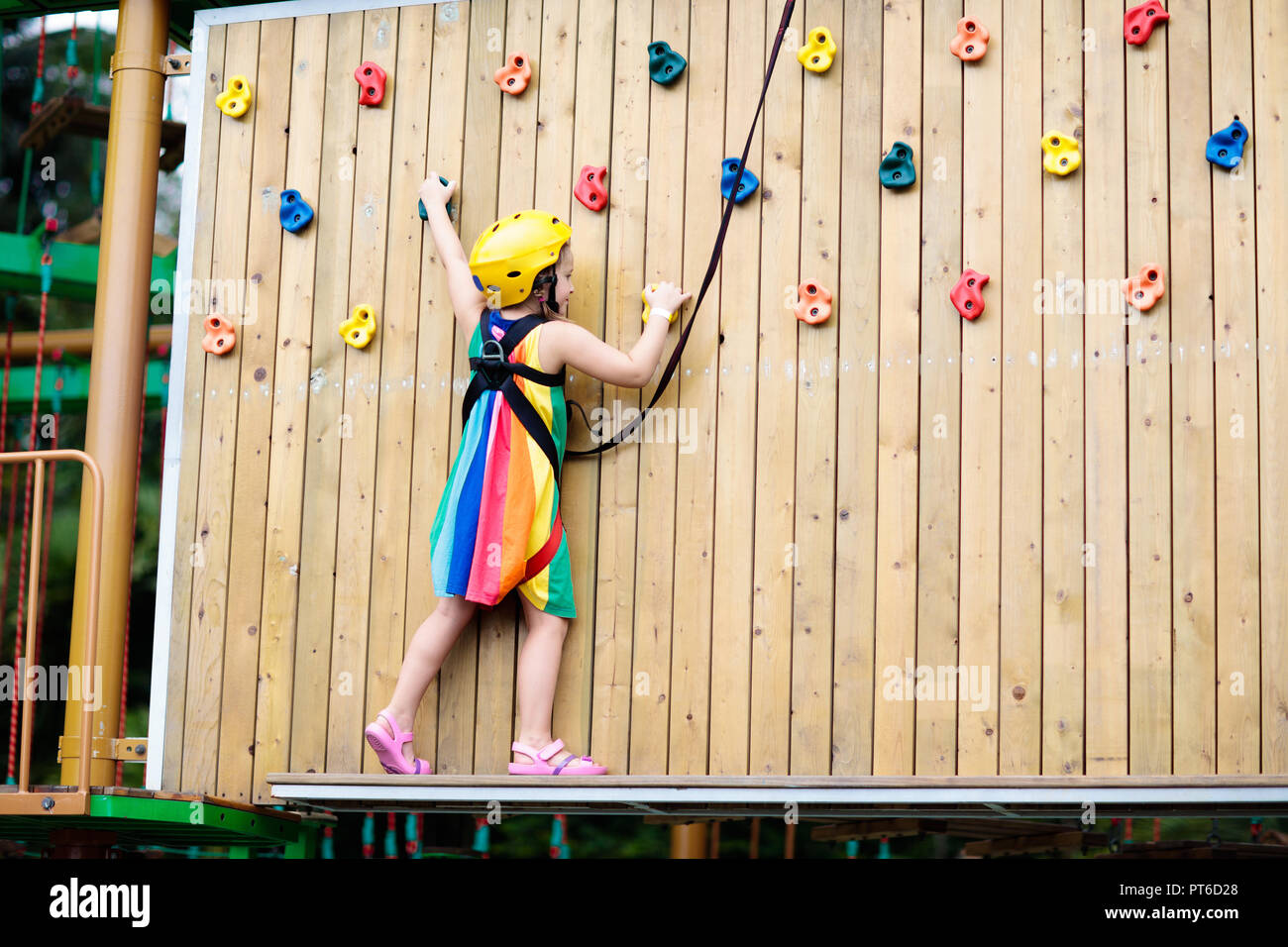 Child in forest adventure park. Kids climb on high rope trail. Agility ...