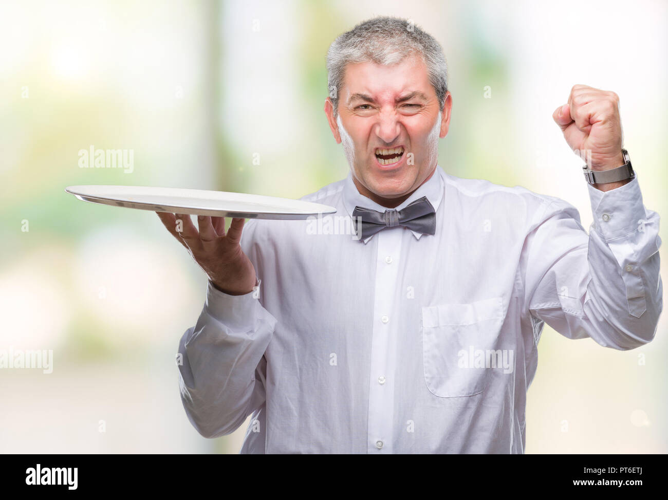 Handsome senior waiter man holding silver tray over isolated background ...
