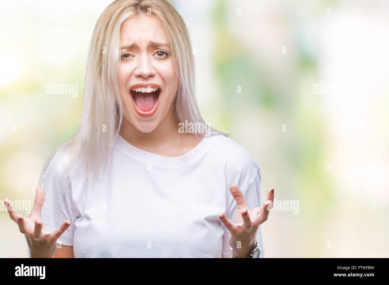 Young blonde woman over isolated background crazy and mad shouting and ...