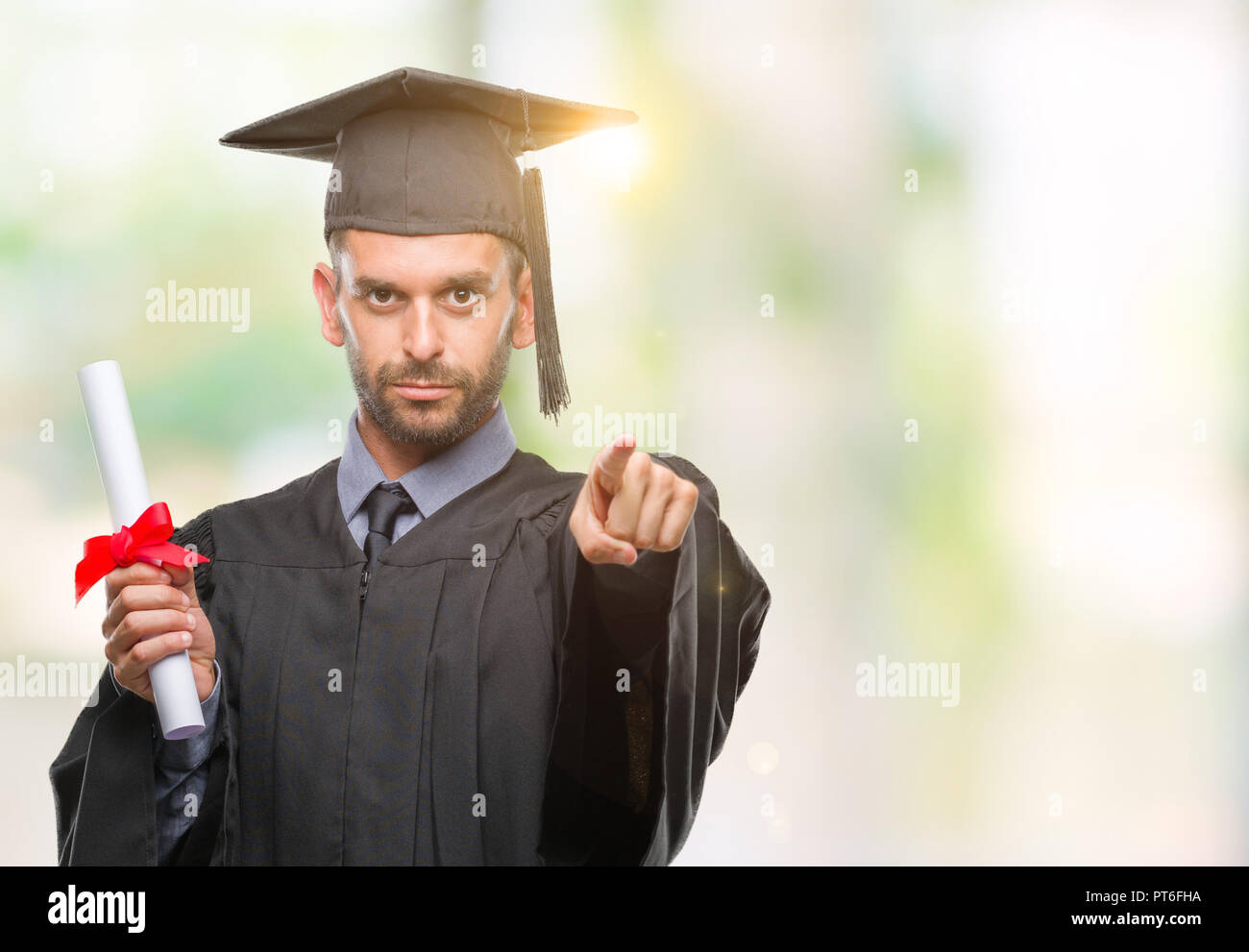 Young handsome graduated man holding degree over isolated background ...