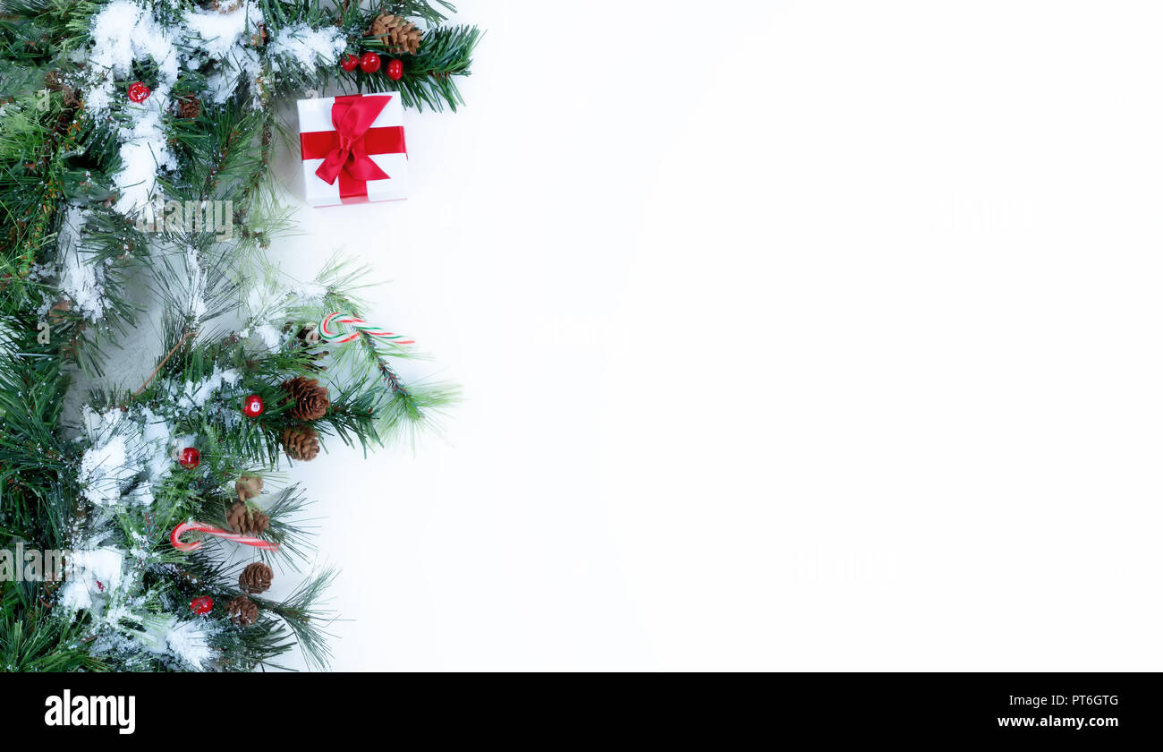 Snow on Christmas tree evergreen branches and decorations on left ...