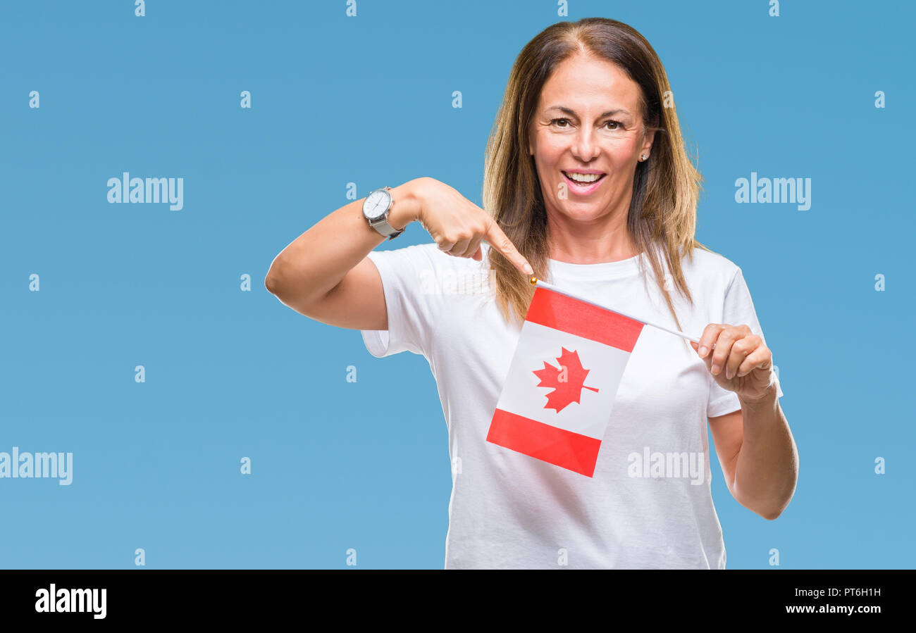 Middle age hispanic woman holding flag of Canada over isolated ...