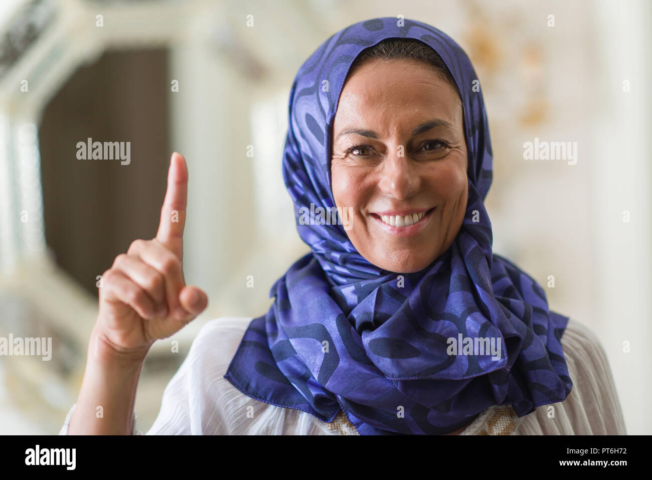 Middle age brunette arabian woman wearing colorful hijab surprised with ...