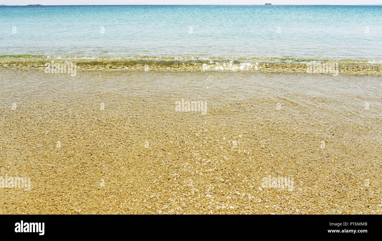 Seascape of translucent clear water shining in the sun. Yellow sand on ...