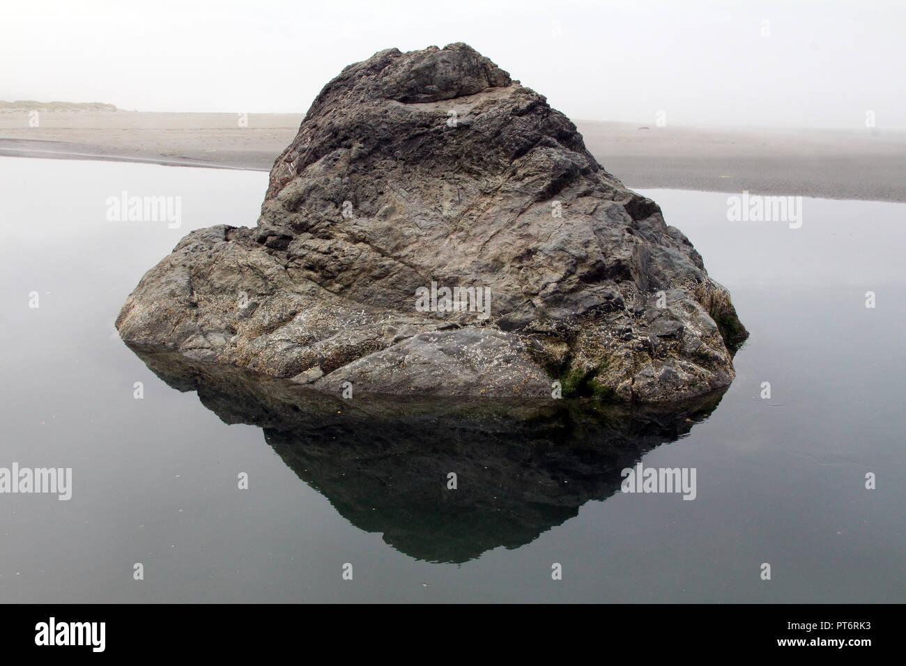 Boulder peeking above still water at Big Lagoon in northern California ...